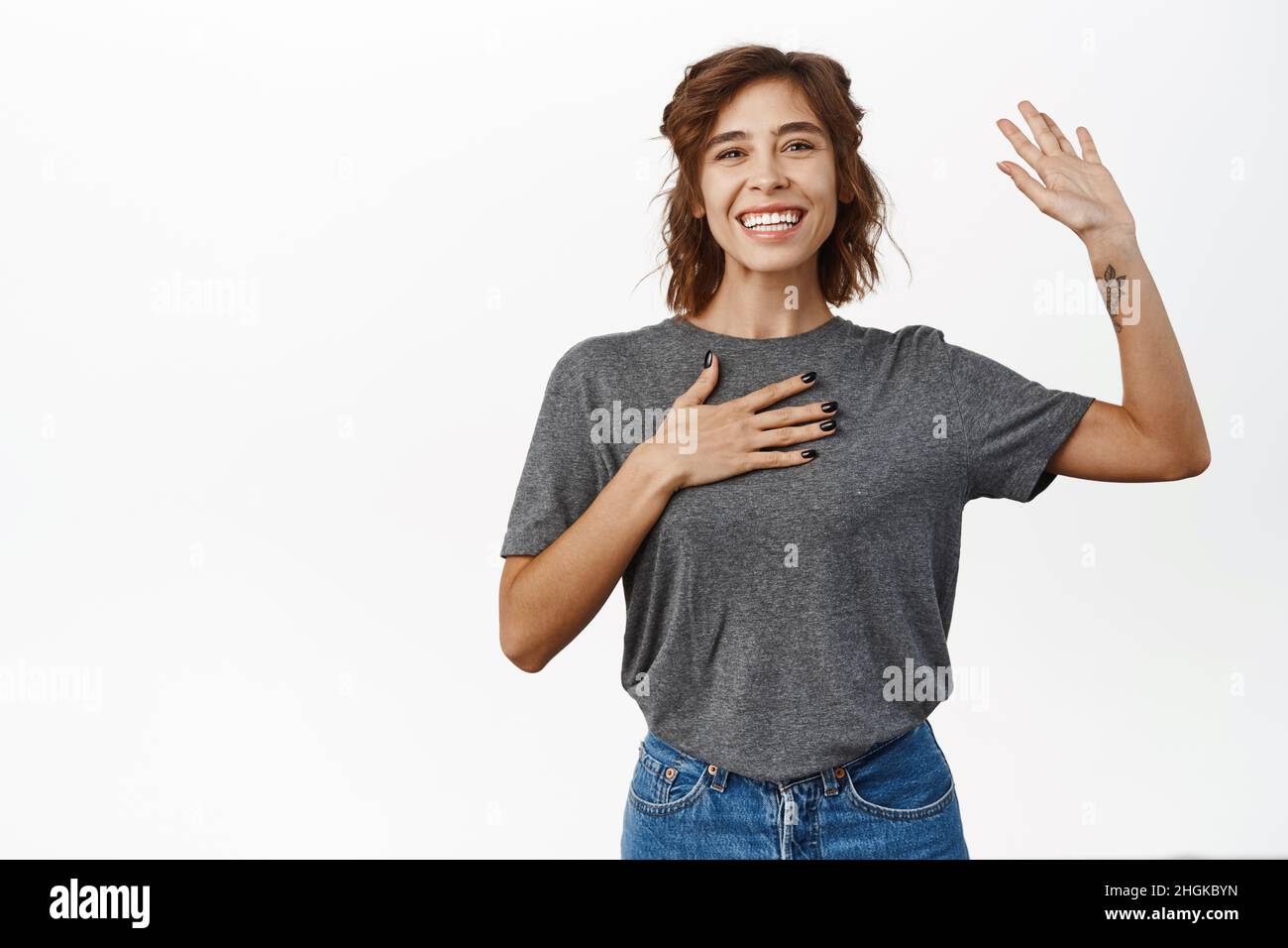 Happy smiling girl saying hello, waving hand, greeting, naming herself ...