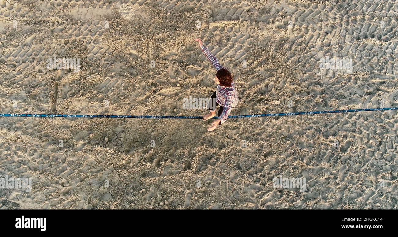 Aerial view above male slackliner balancing on rope and doing ...
