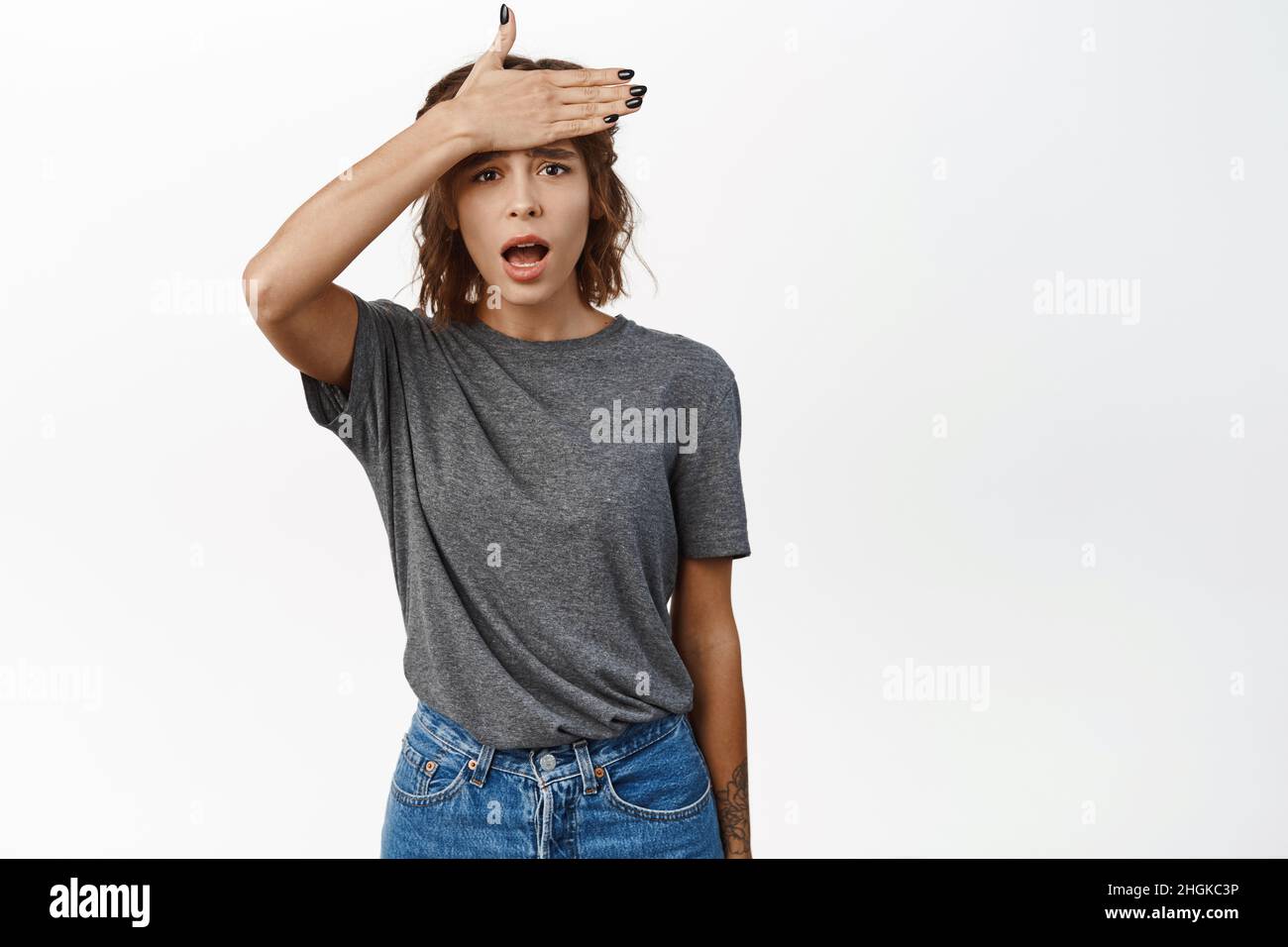 Shocked and worried young woman slap forehead, facepalm, staring ...