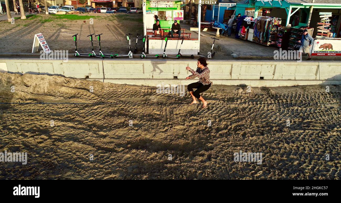 Aerial view above male slackliner balancing on rope and doing ...