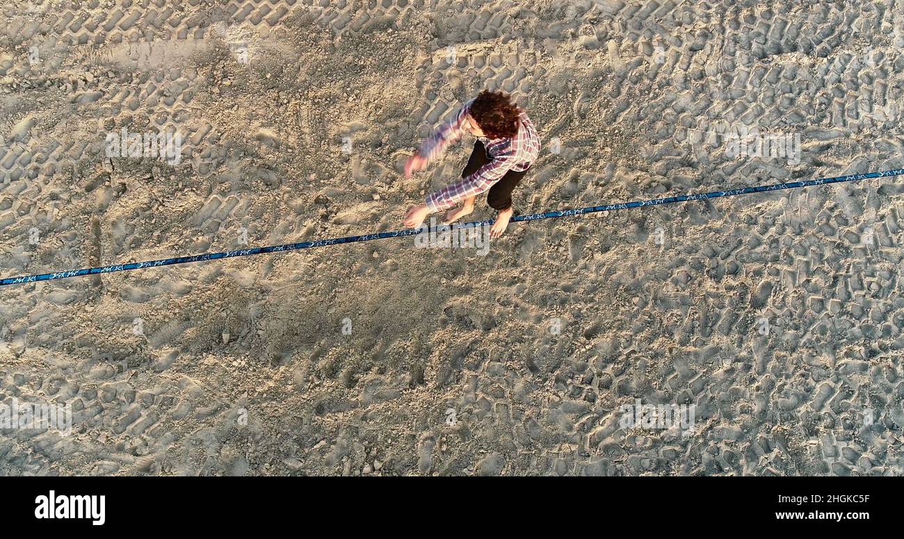 Aerial view above male slackliner balancing on rope and doing ...
