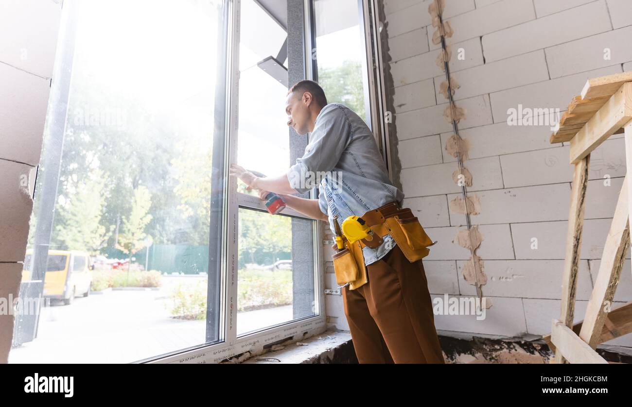 Construction worker installing window in house Stock Photo - Alamy