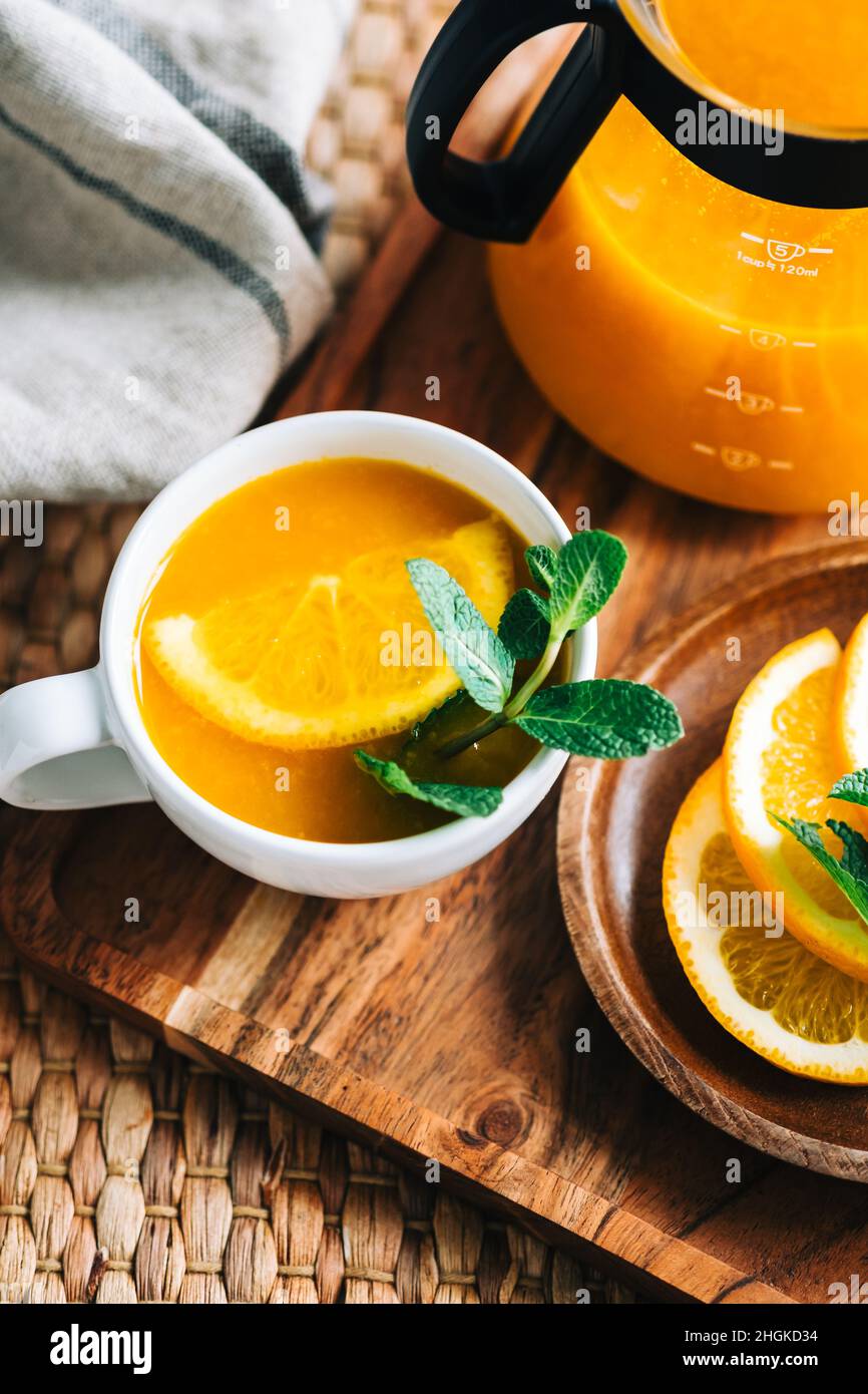 Brewed sea buckthorn tea in a teapot with orange in glass cups with fresh orange, mint and honey ...