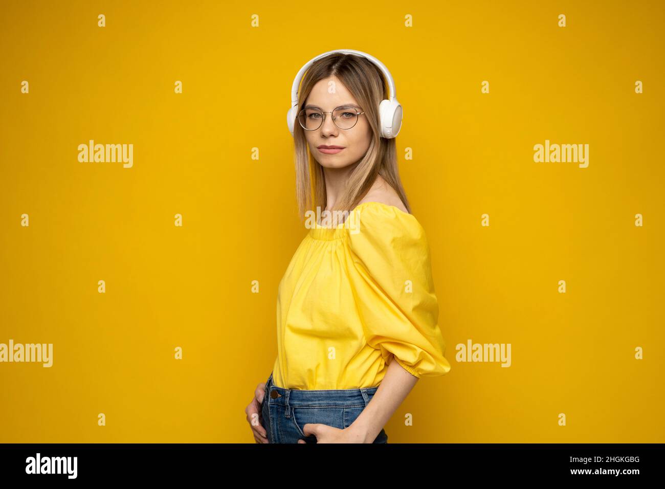 Pretty young woman girl in yellow t-shirt listen music with headphones ...
