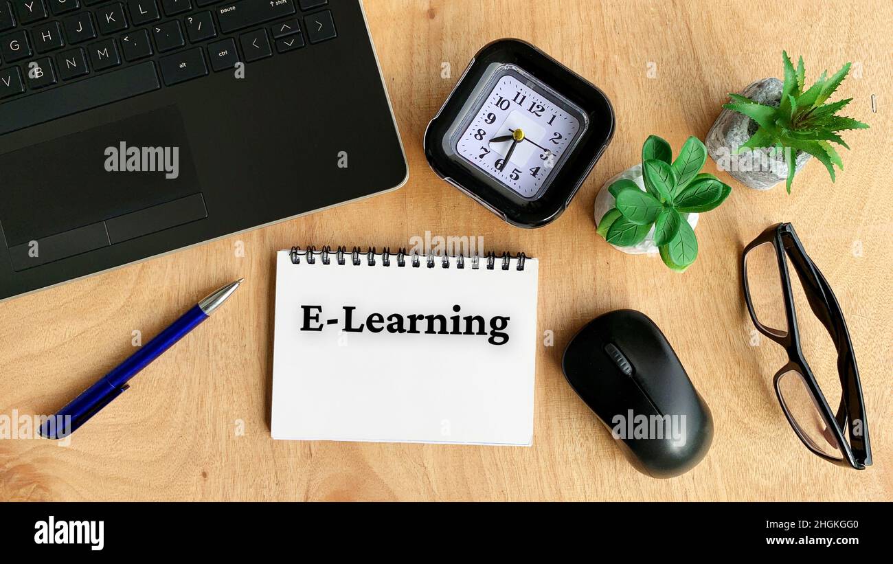 E-learning text on notepad with laptop, pen, mouse, plant and brown ...