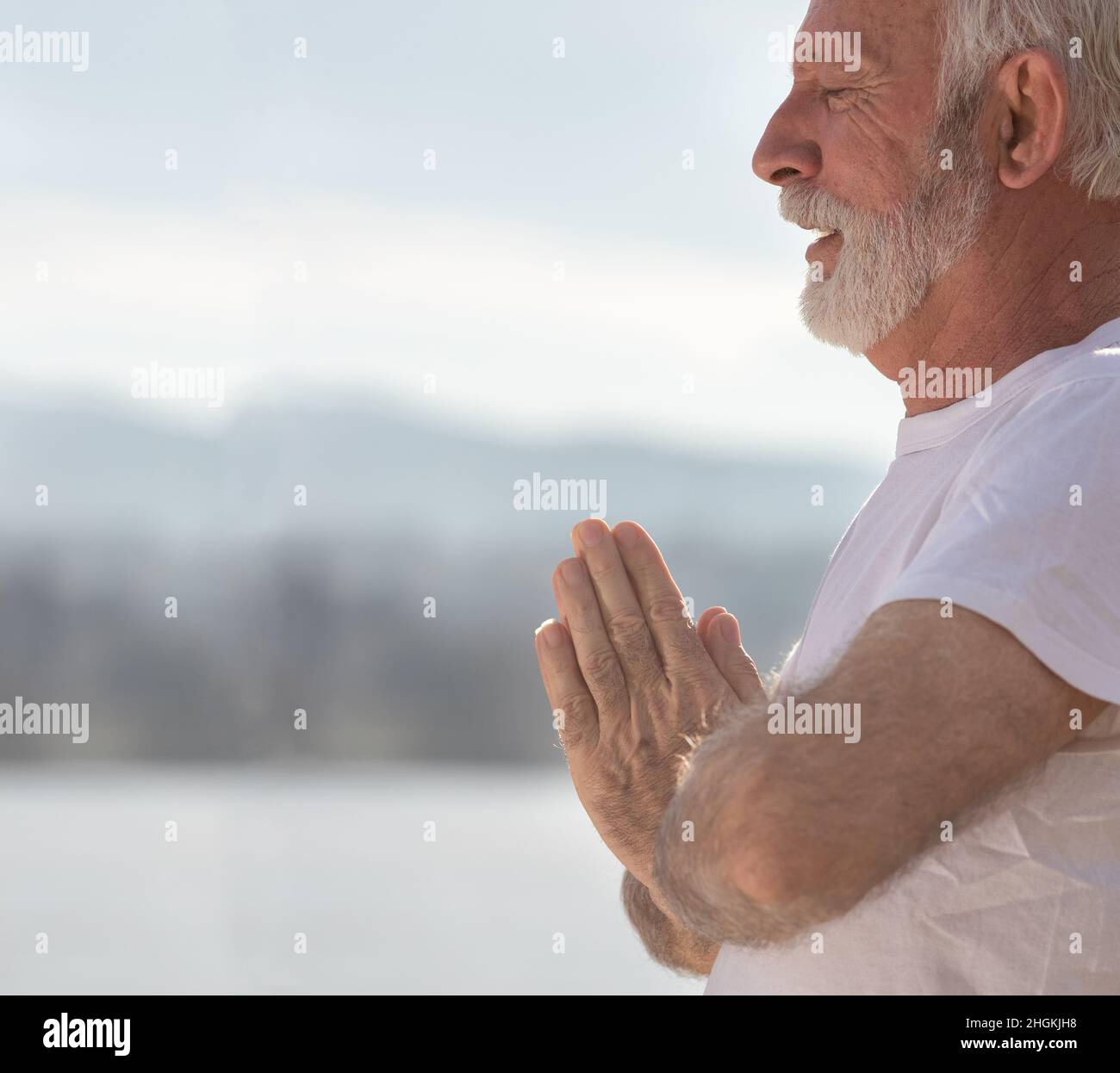 Portrait of senior man holding namaste pose and meditating outdoor ...