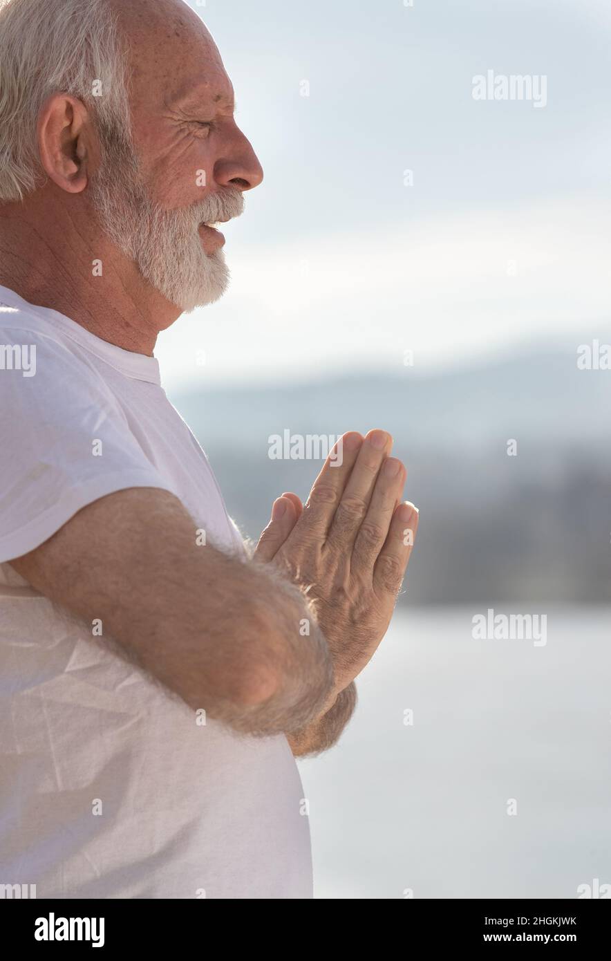 Portrait of senior man holding namaste pose and meditating outdoor ...