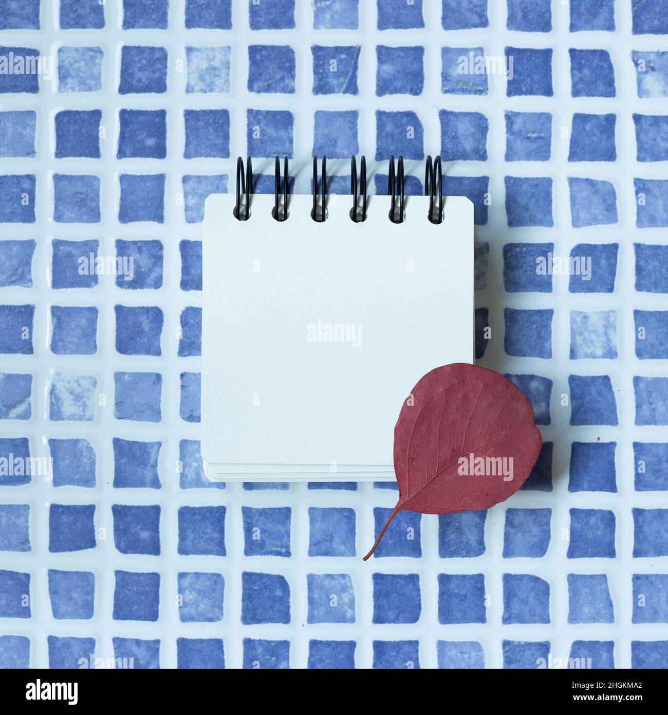 Blank white notepad on blue ceramic mosaic table. top view, copy space ...