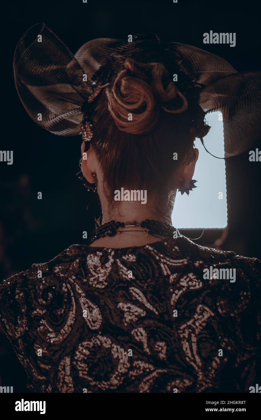 Back view of brunette young woman with vintage headdress and outfit ...
