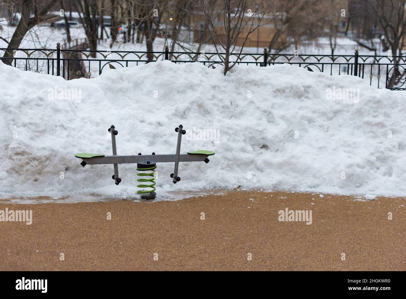 Children's swing at the snow pile. Poorly cleared of snow playground in ...