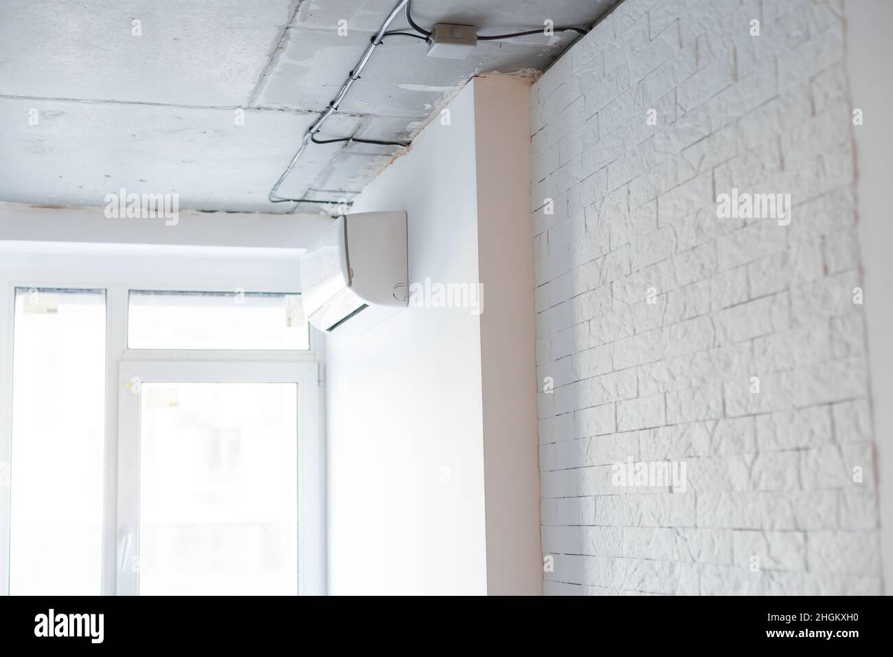shot of newly installed white air conditioner. Working AC hanging on the pastel color wall with ...