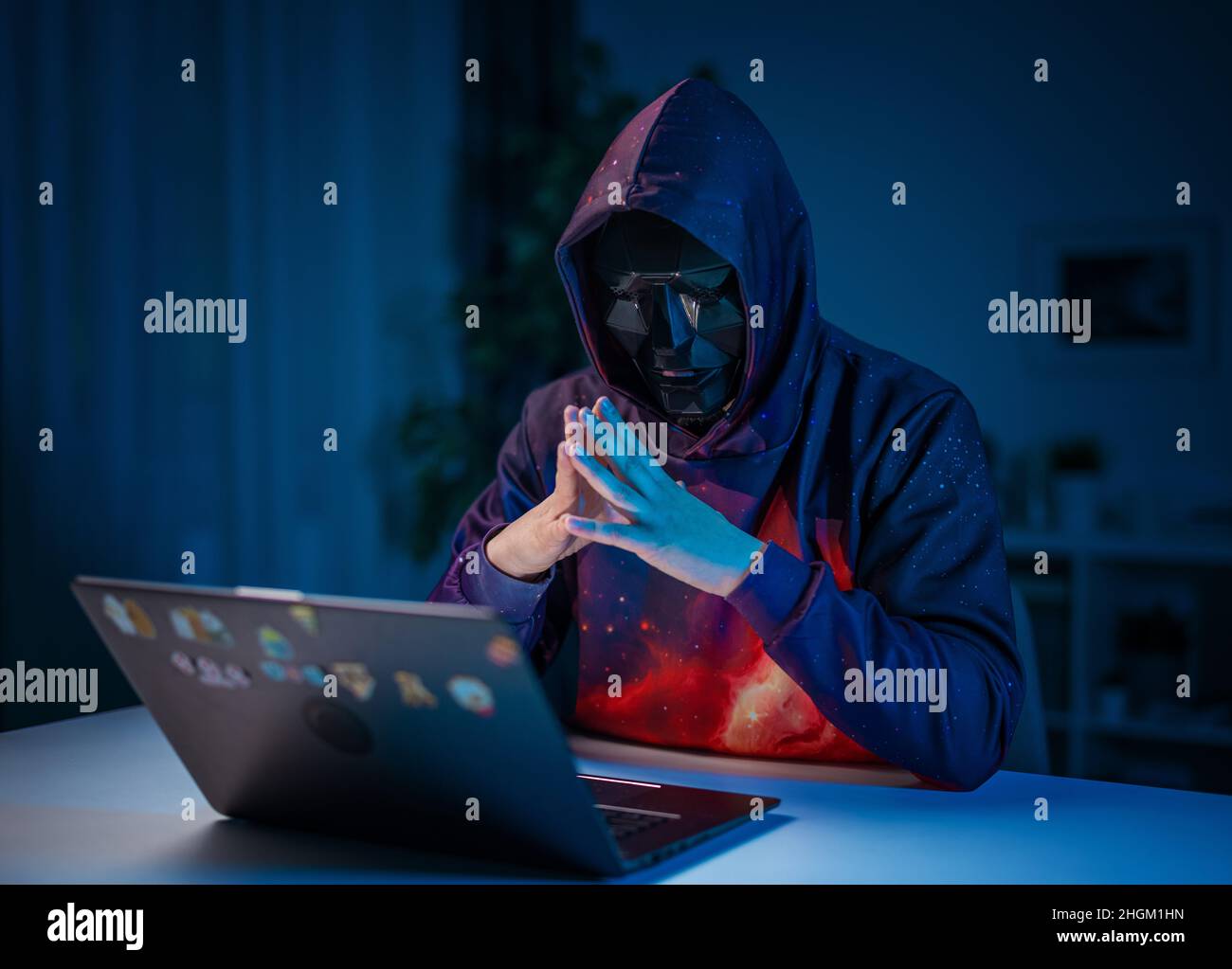 Hacker in mask work on laptop Stock Photo - Alamy