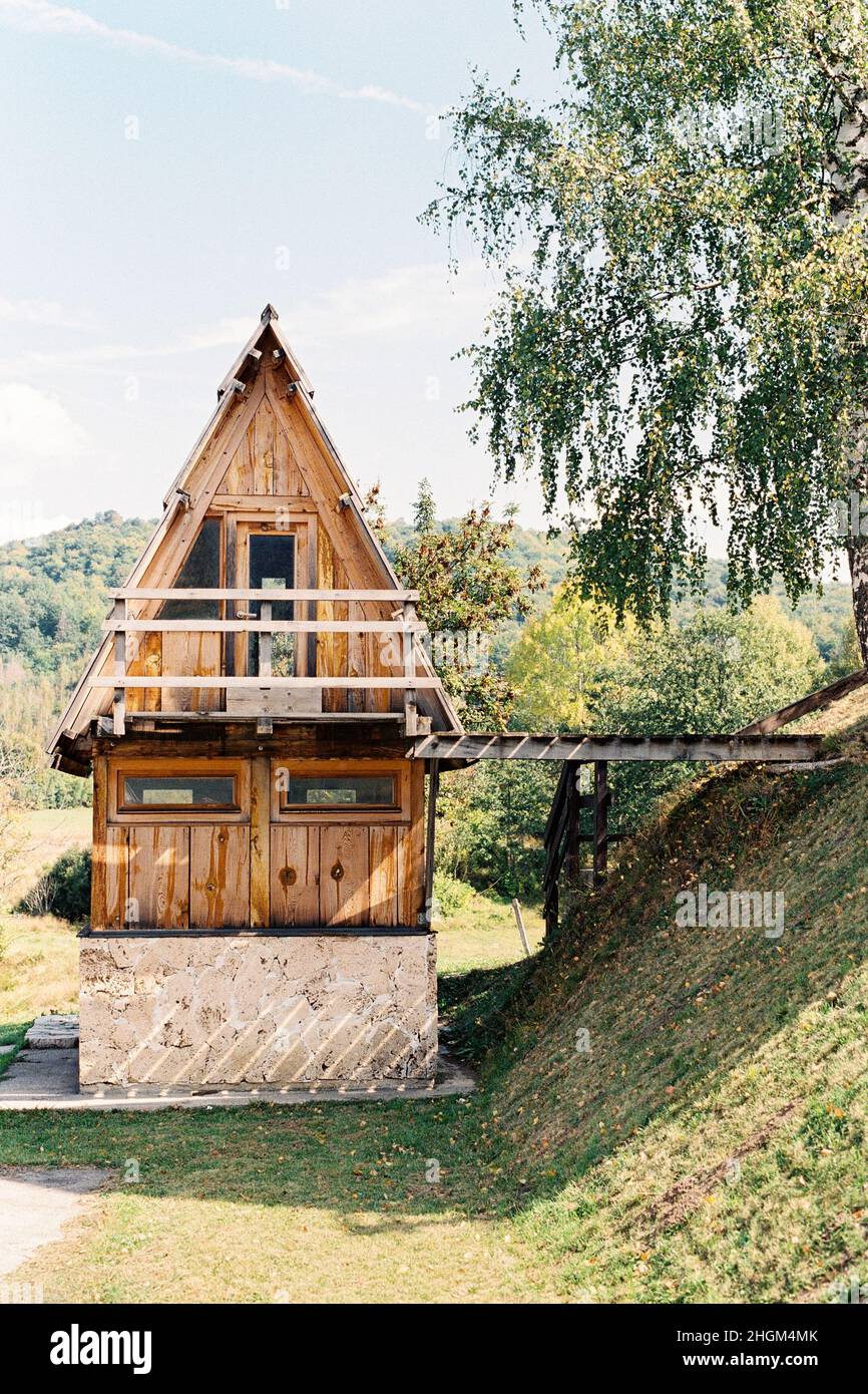 Triangular two-story house with a wooden bridge to the hill Stock Photo ...