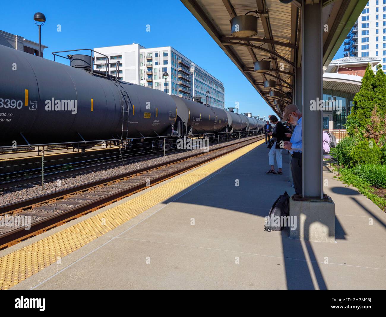 Commuters waiting for morning train and parked freight train with tank ...