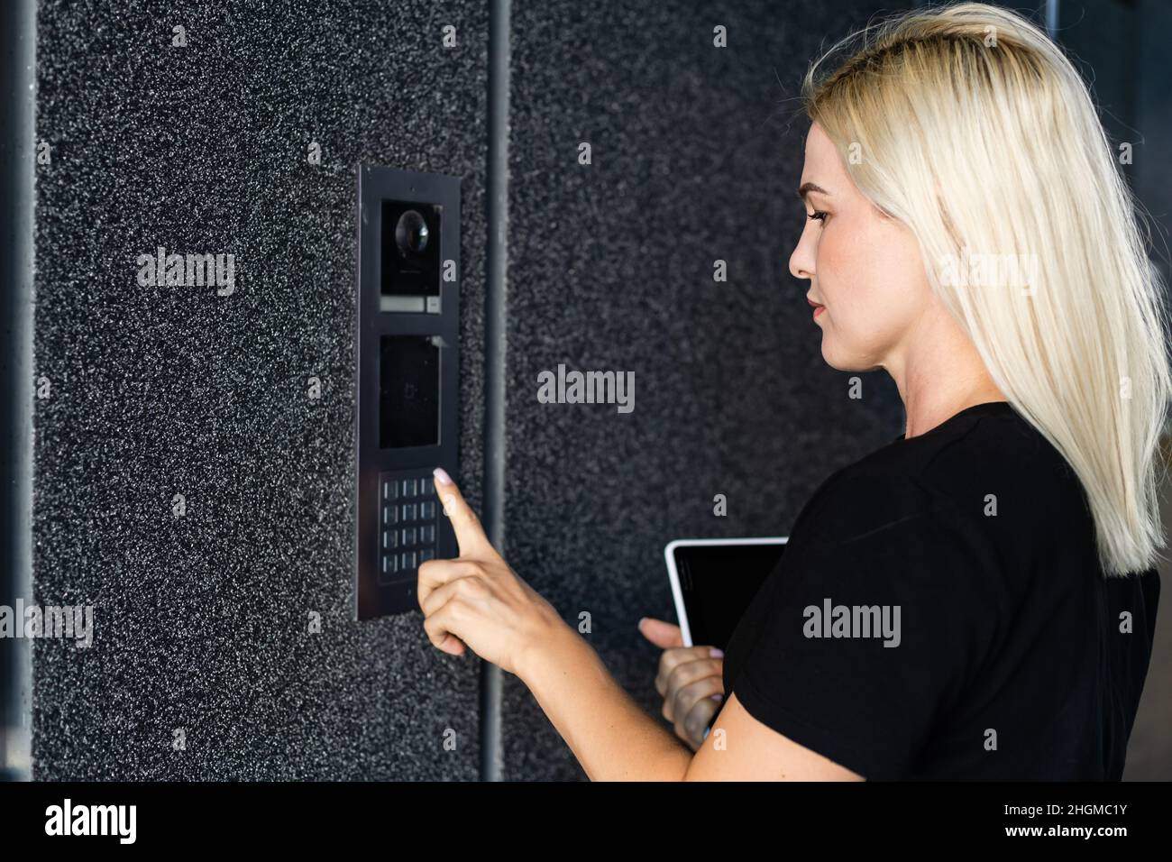 woman dialing an intercom to enter a building Stock Photo - Alamy