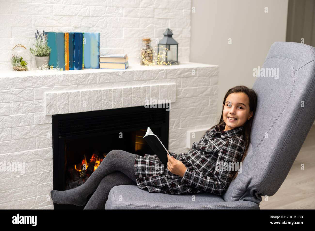 little cute girl sitting n and reading book. Cozy interior Stock Photo ...
