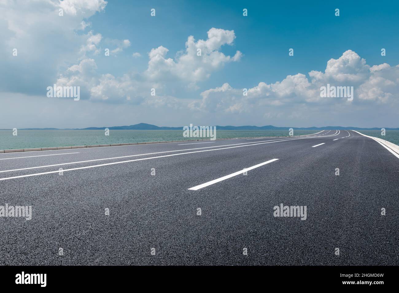 Asphalt road and river with mountains under blue sky Stock Photo - Alamy