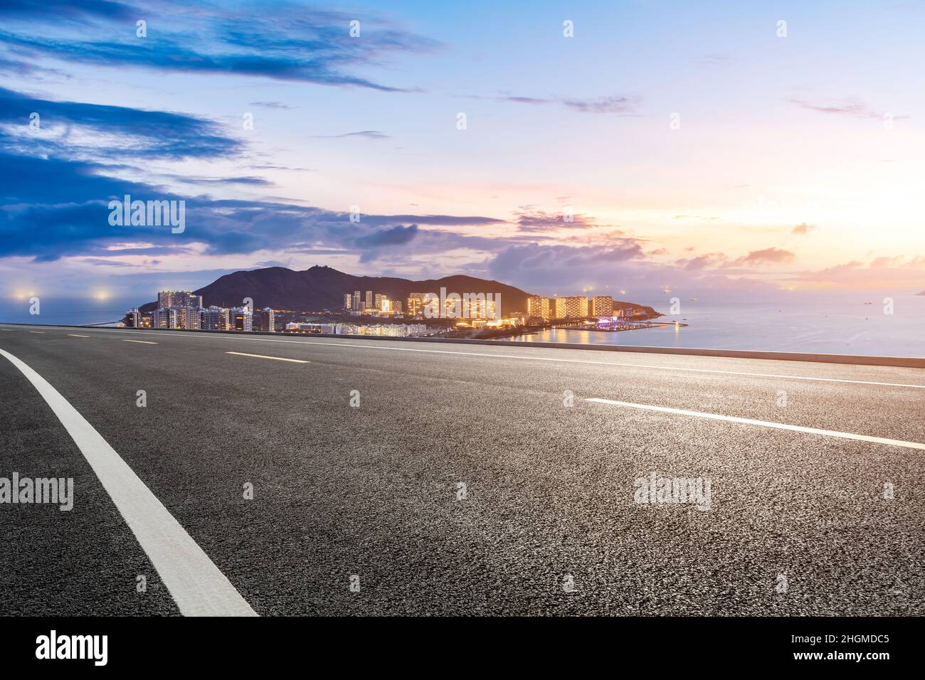 Asphalt road and modern city skyline with buildings at sunset Stock ...