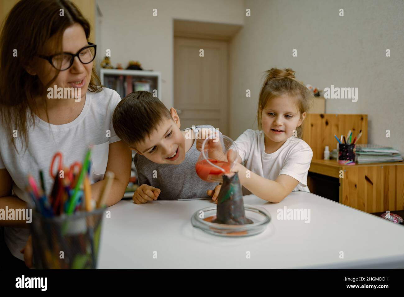 Mom and children at home are conducting an experiment with a volcanic ...
