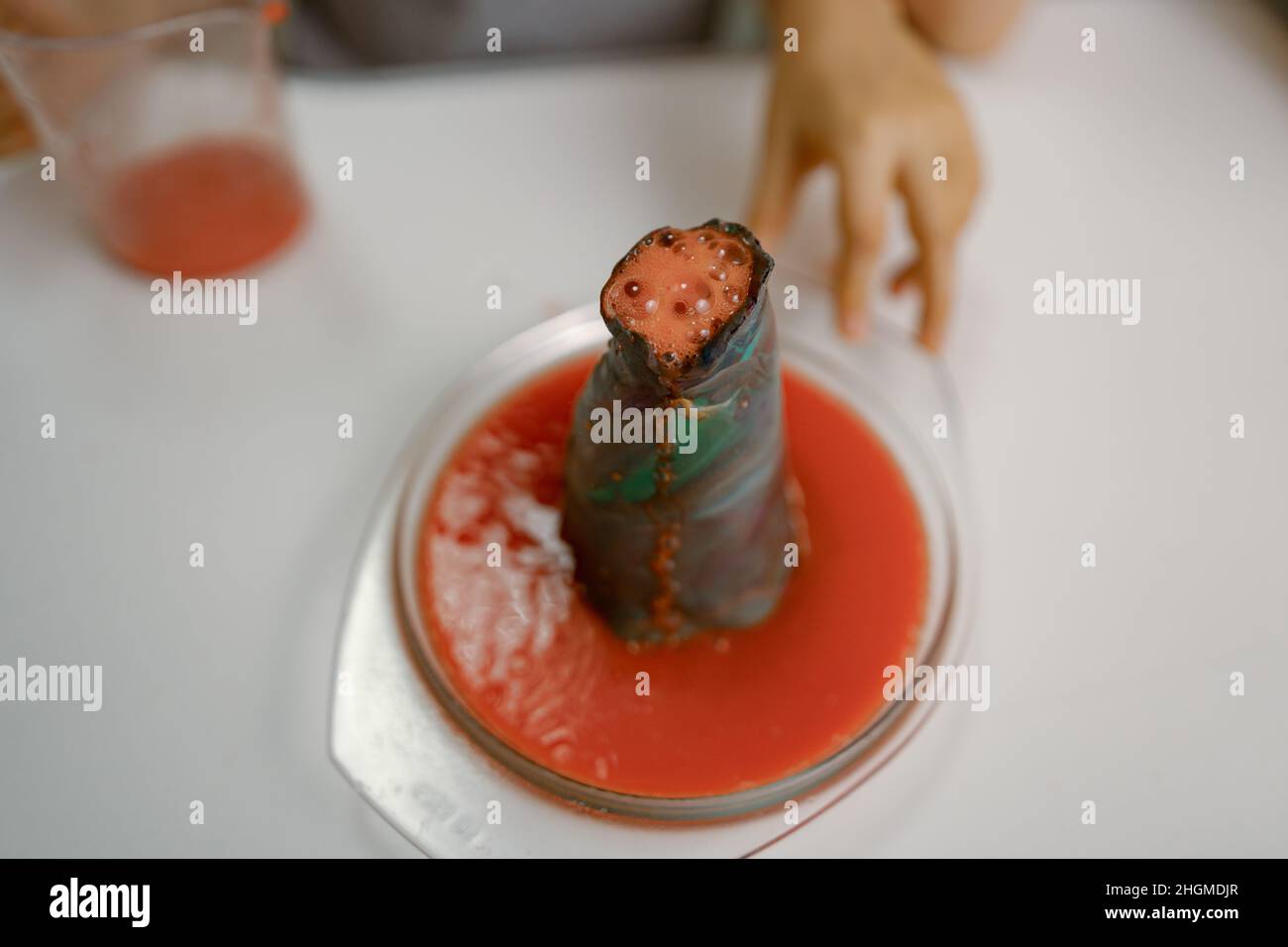 Mouth of a plasticine volcano with red eruption, close-up on the table ...