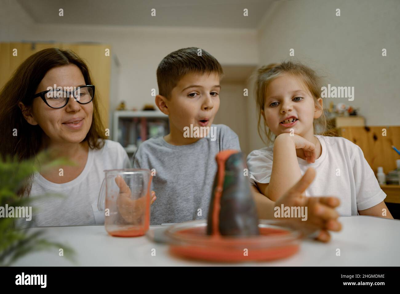 Mom and children at home are conducting an experiment with volcanic ...