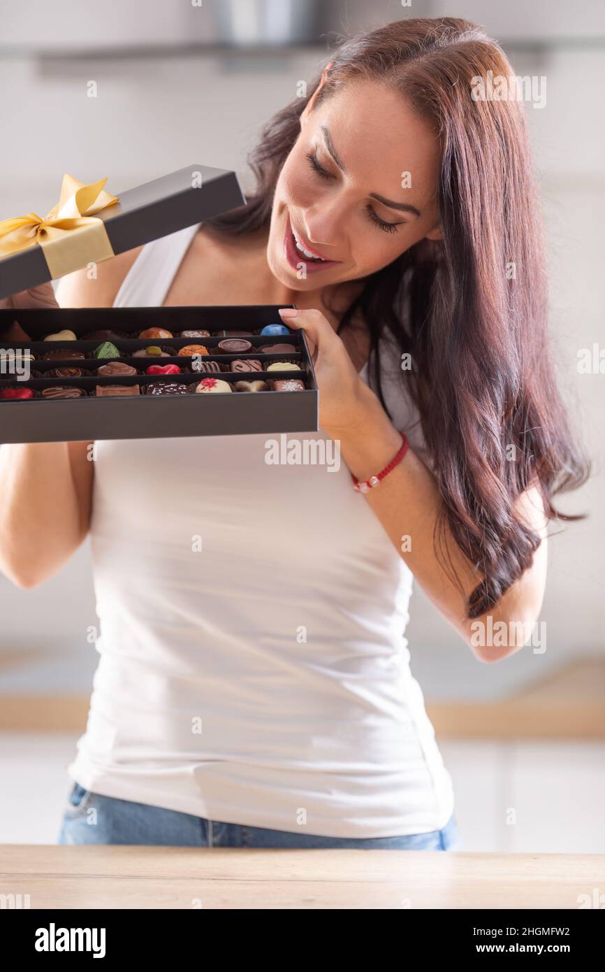 Curious woman peeks inside a chocolate box with selection of various ...