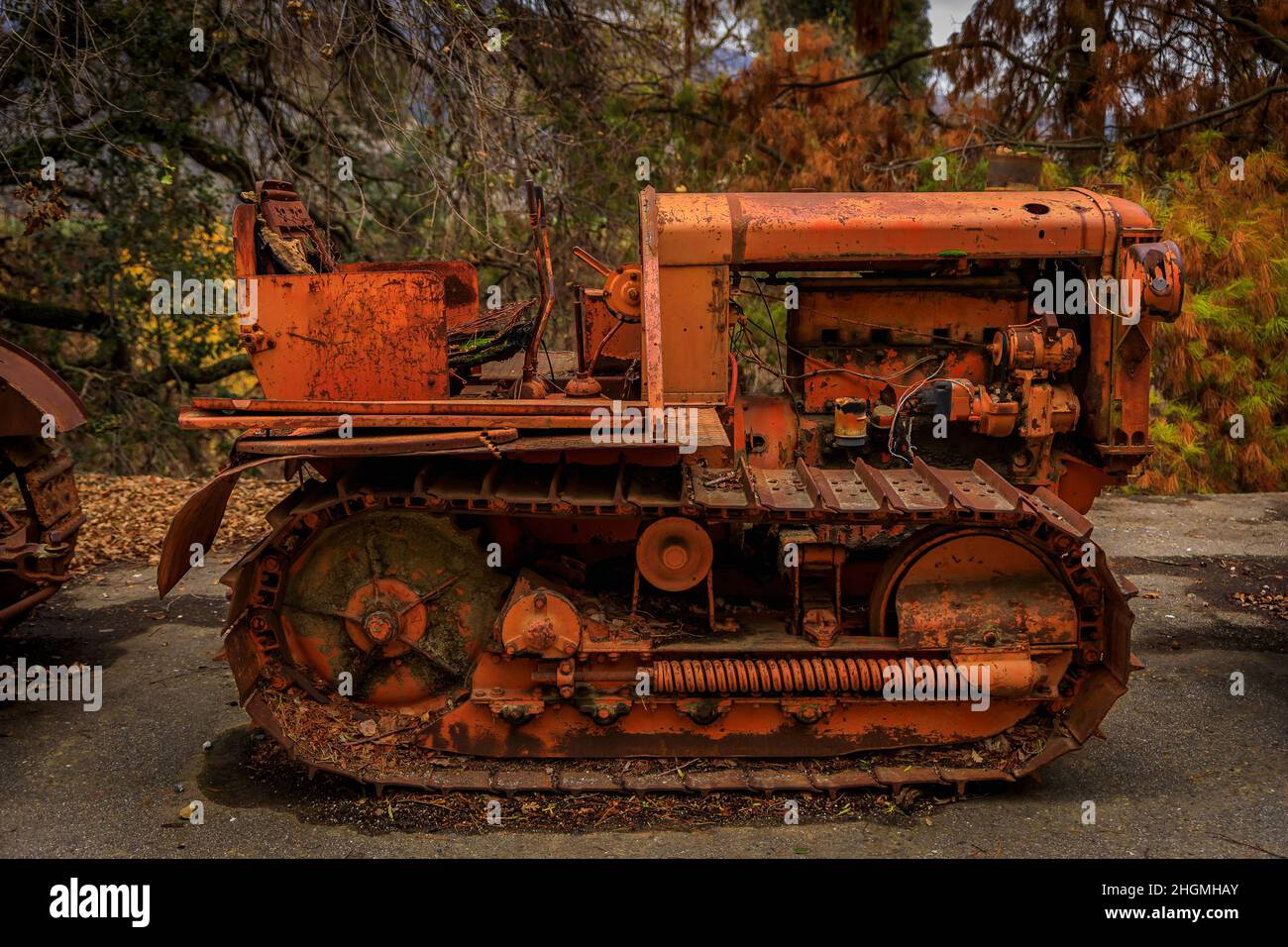 Old rusty abandoned heavy equipment, tread tractor, amongst trees with ...