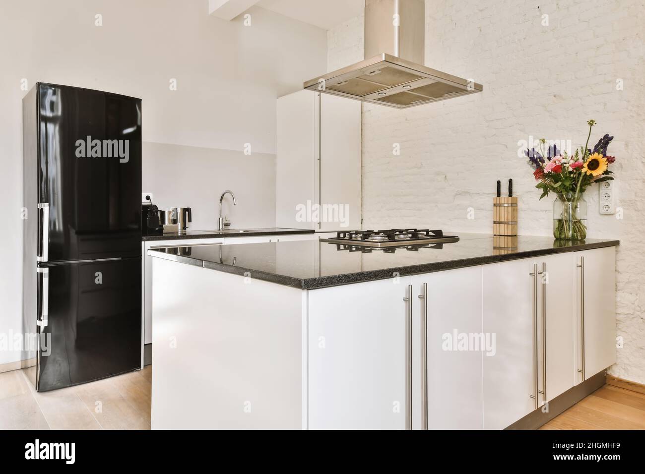 Comfortable kitchen with white kitchen unit and black marble countertop ...