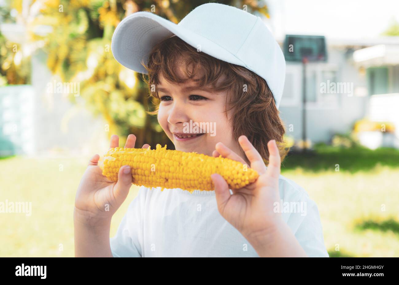 Kid boy having fun with food vegetables corn. Child in the garden, corn ...