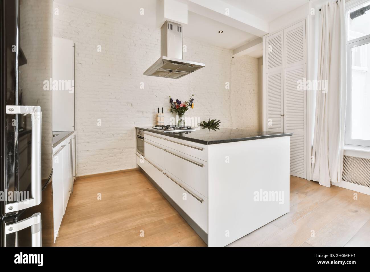Comfortable kitchen with white kitchen unit and black marble countertop ...