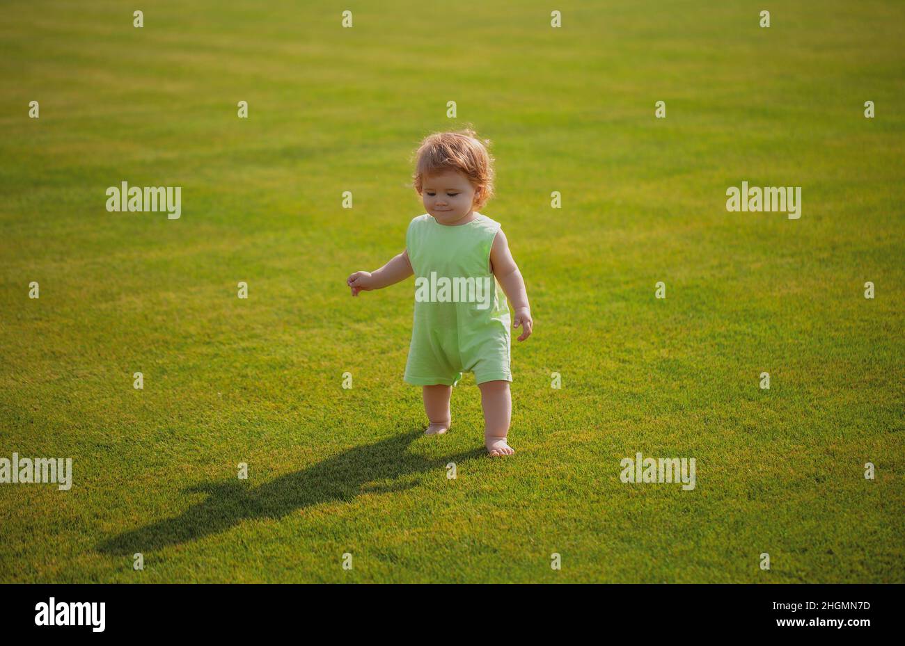 Little baby learning to crawl steps on the grass. Concept childrens ...