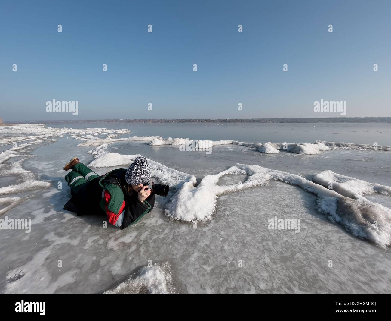 Authentic woman photographer taking pictures of natural frozen lake ...