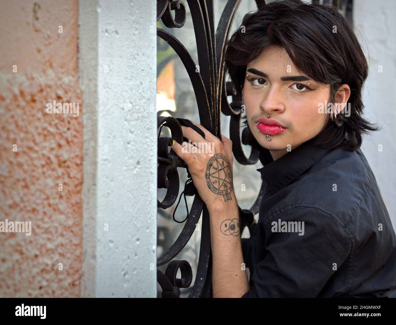 Young handsome Latino Mexican man with red lipstick, hand tattoo and ...