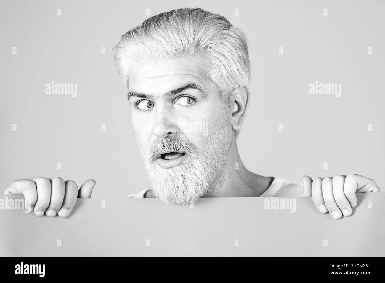 Funny man shows a sheet of paper in the camera on a yellow background ...