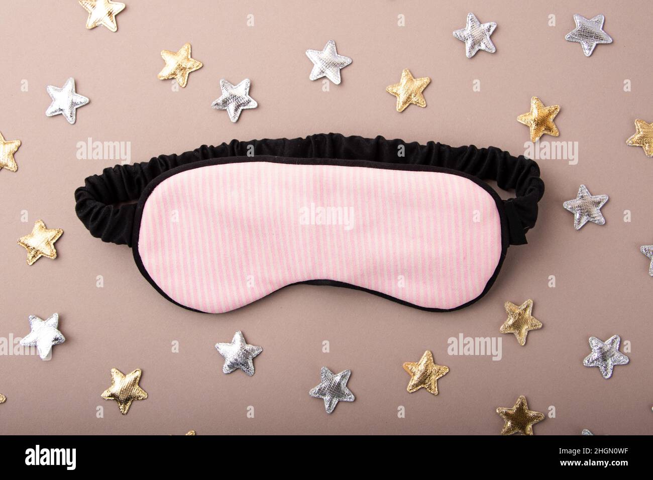 Mask for sleep on the pastel background.Golden and silver stars around ...