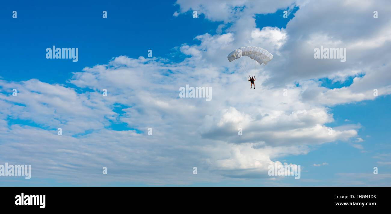 Parachutist is flying slowly down with an open parachute. Skydiving ...