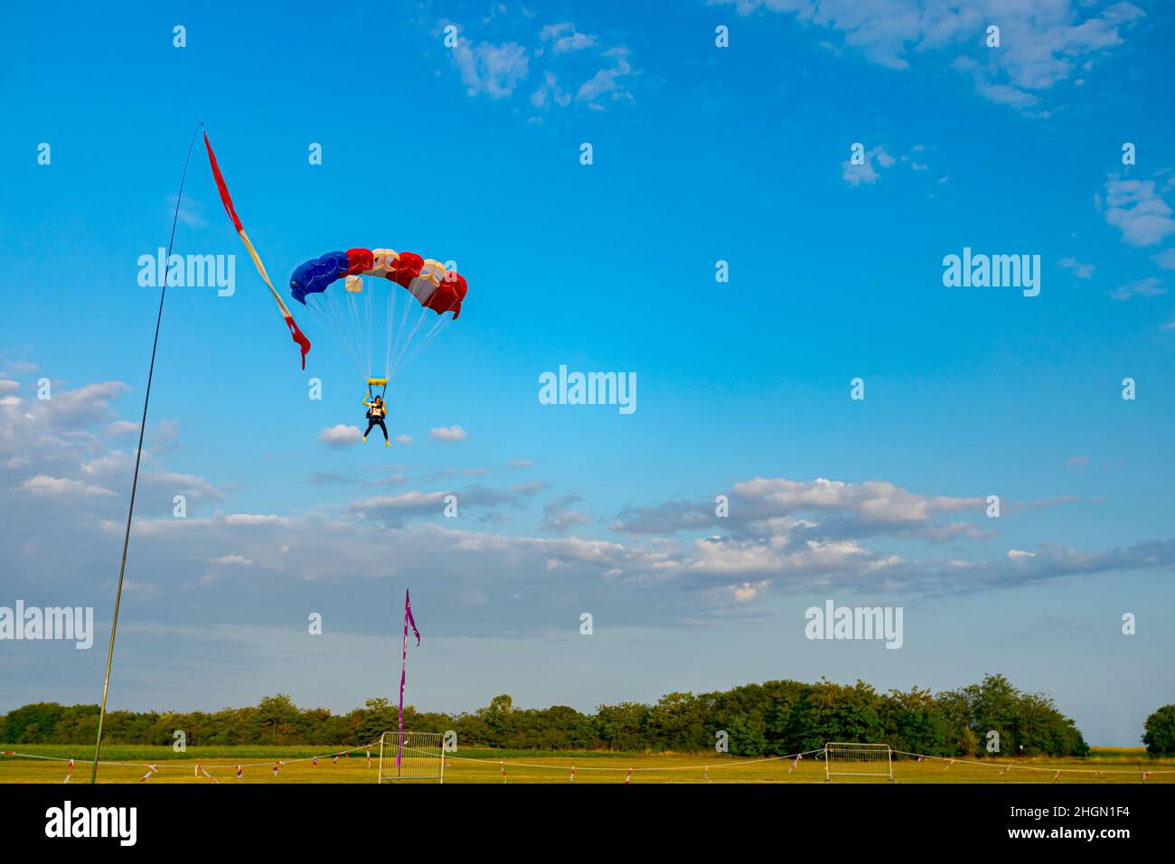 Parachutist with an open parachute is flying and slows down for landing ...