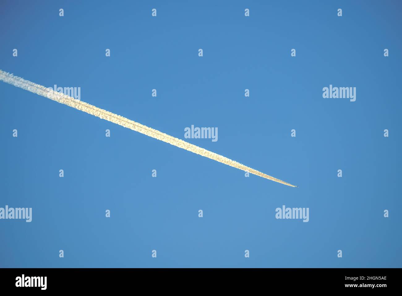 high altitude contrails from a twin engine jet aircraft in a clear blue ...