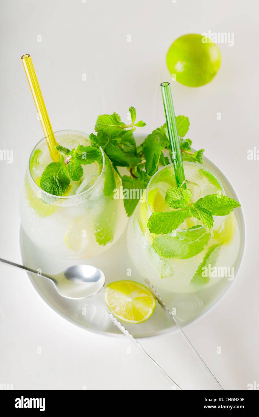 Two mojito glasses with straws. Mojito cocktail with lime and mint on ...