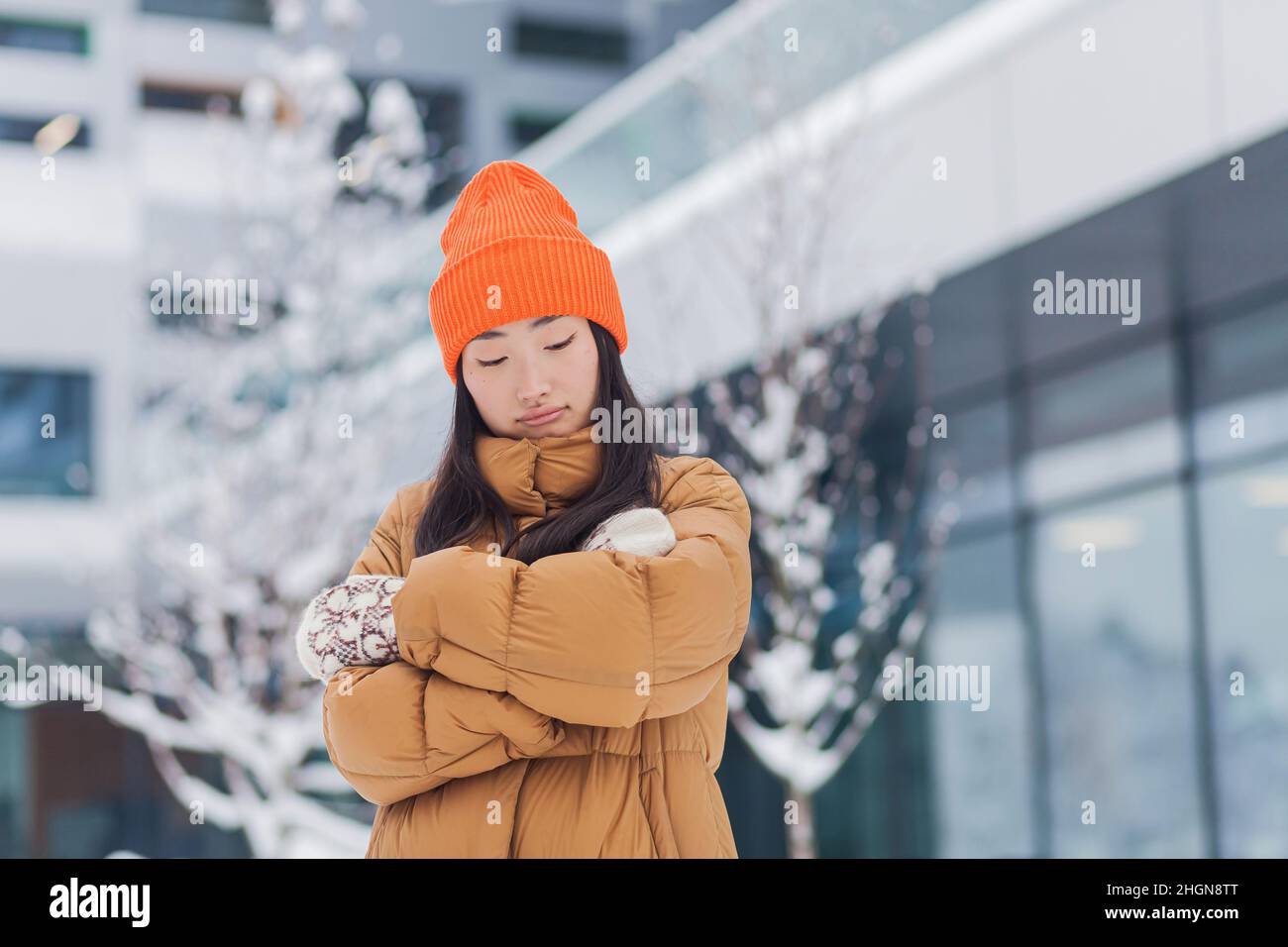 Asian woman on the street frozen in the cold, on a winter snowy day ...
