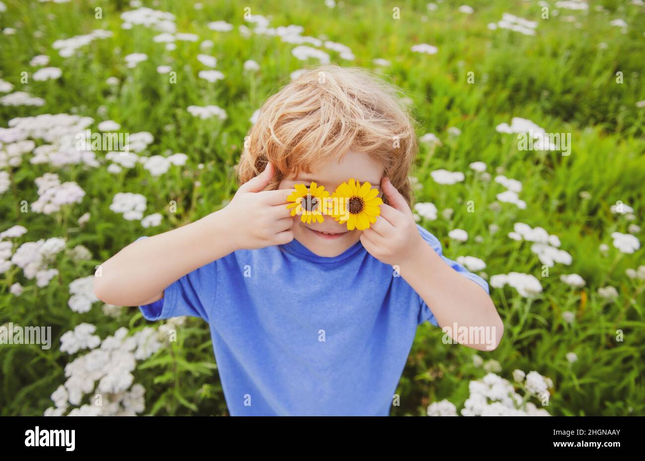 Spring kid. Funny little boy with daisy in eyes Stock Photo - Alamy