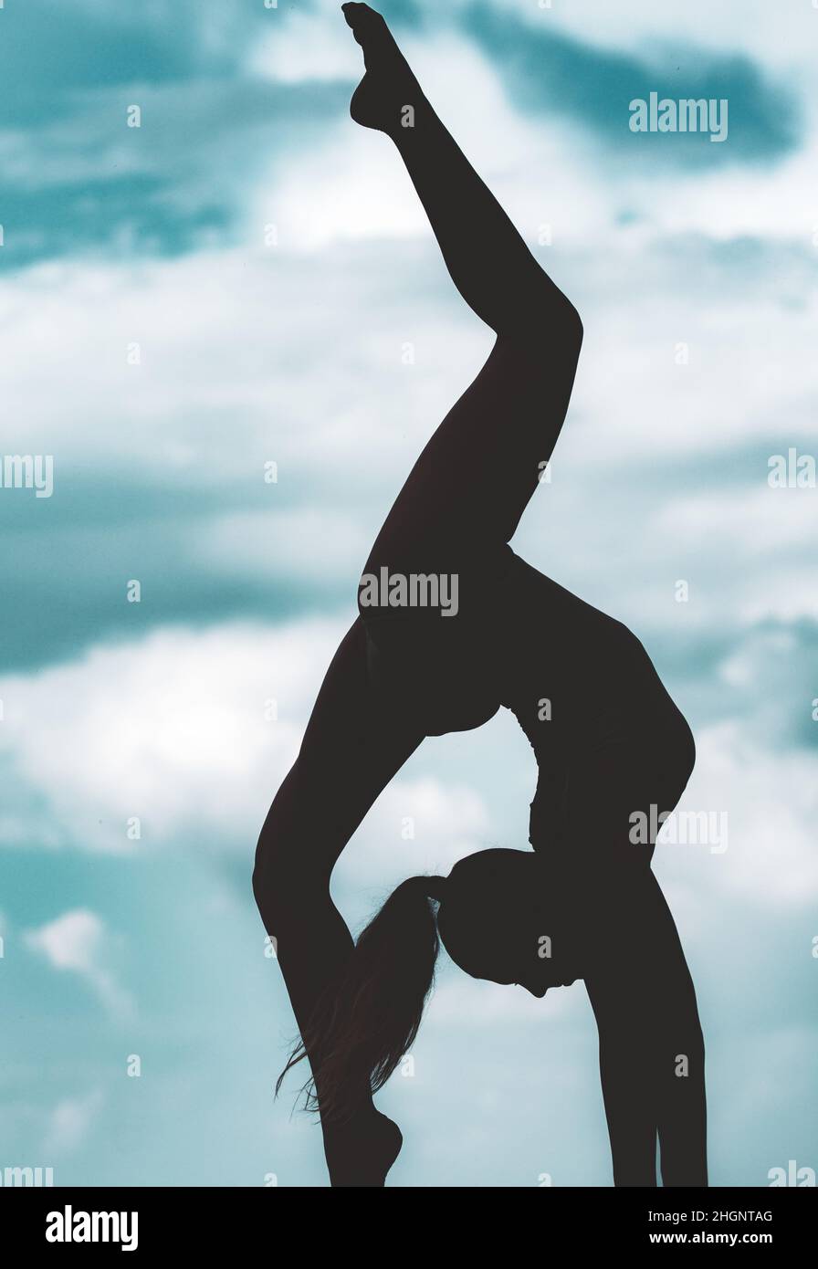 Girl gymnastic silhouette on sky. Young slender girl doing acrobatic ...