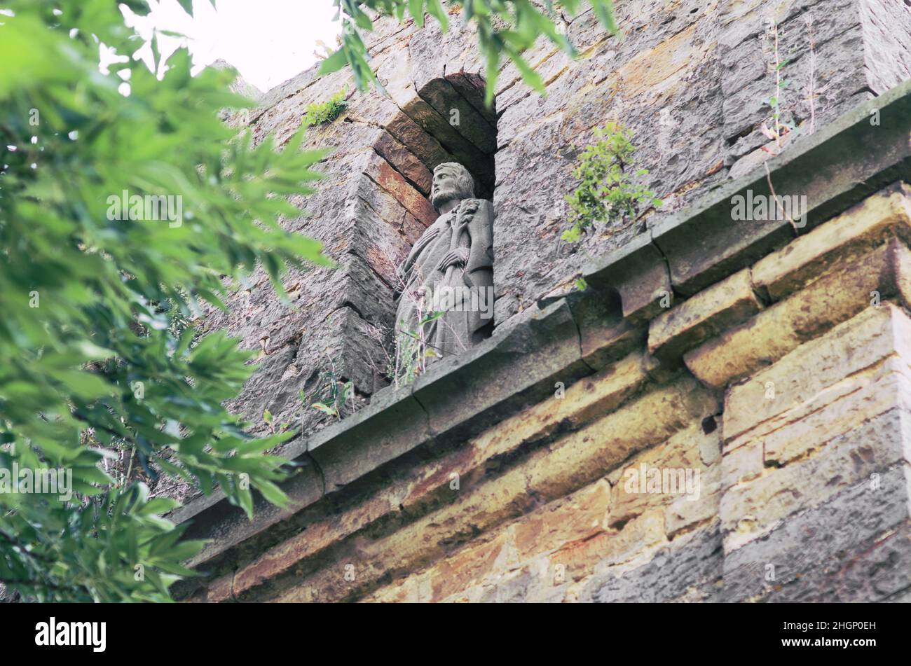 Ancient statue in arch of stone wall. Part of ruined stone church ...