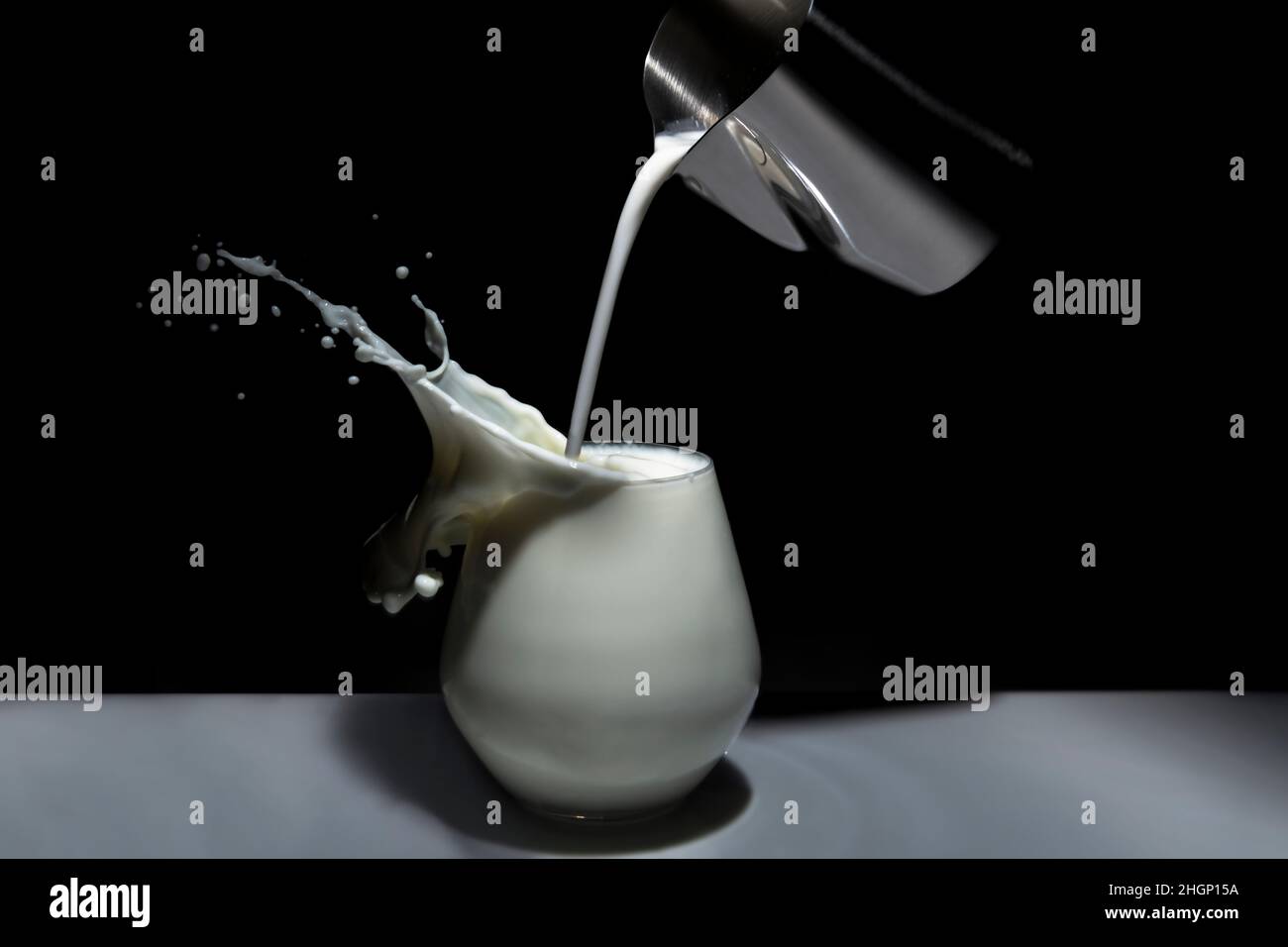 Pitcher pouring milk into a glass. Selective focus Stock Photo - Alamy
