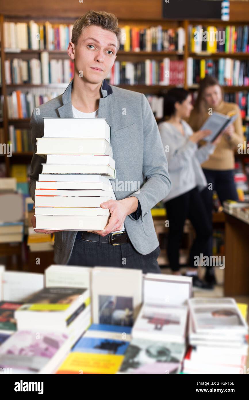 student standing in library with pile of books Stock Photo - Alamy