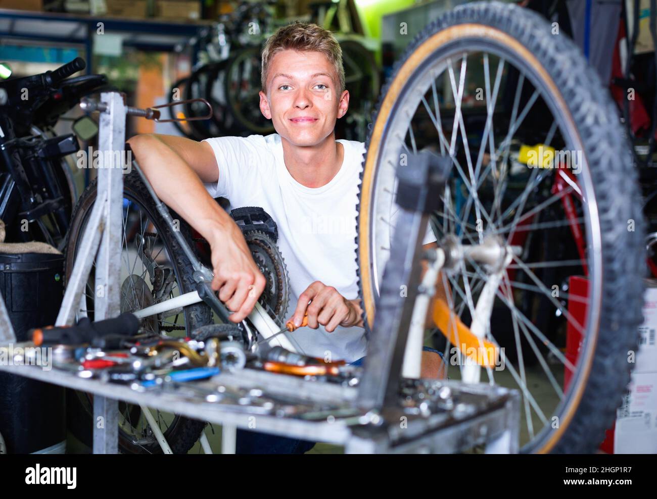 Man repairing bicycles with instruments indoors Stock Photo - Alamy