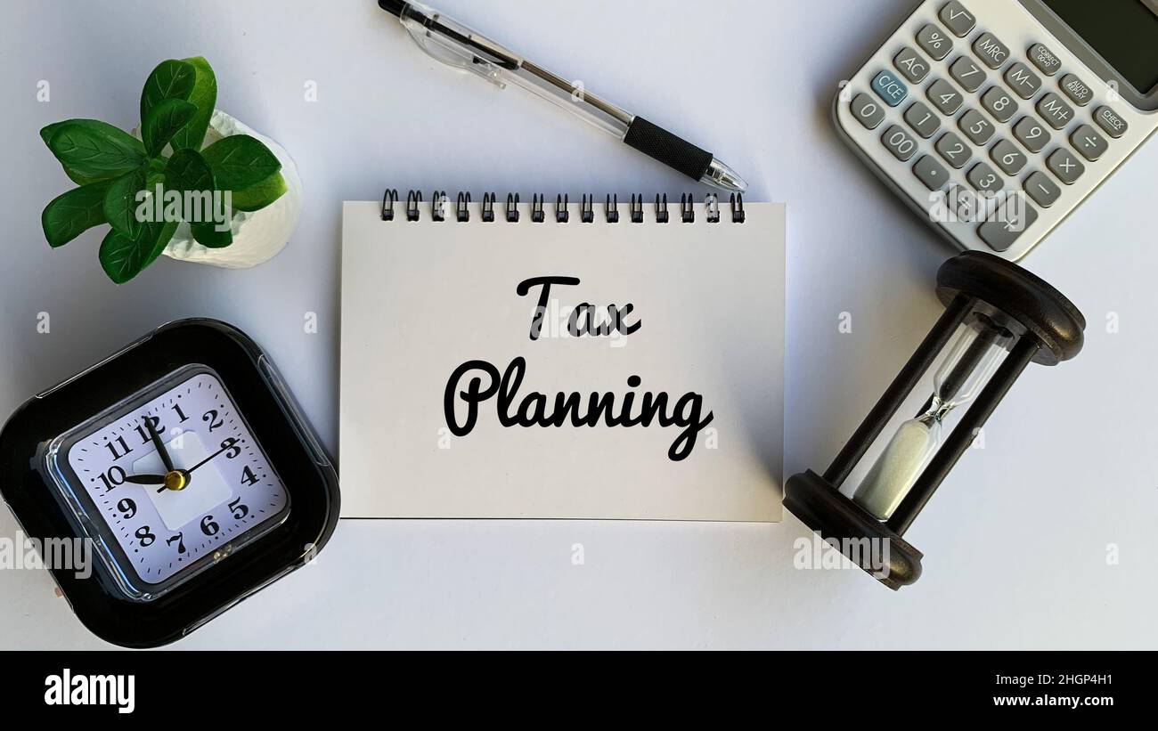 Tax planning text on notepad with calculator, clock and pen background ...