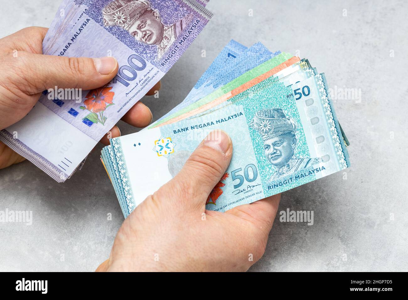 Malaysian money held in both hands, Lots of ringgit, Gray background ...