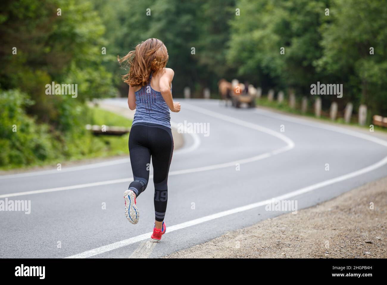 Runner woman running on the mountain road through the forest Stock ...