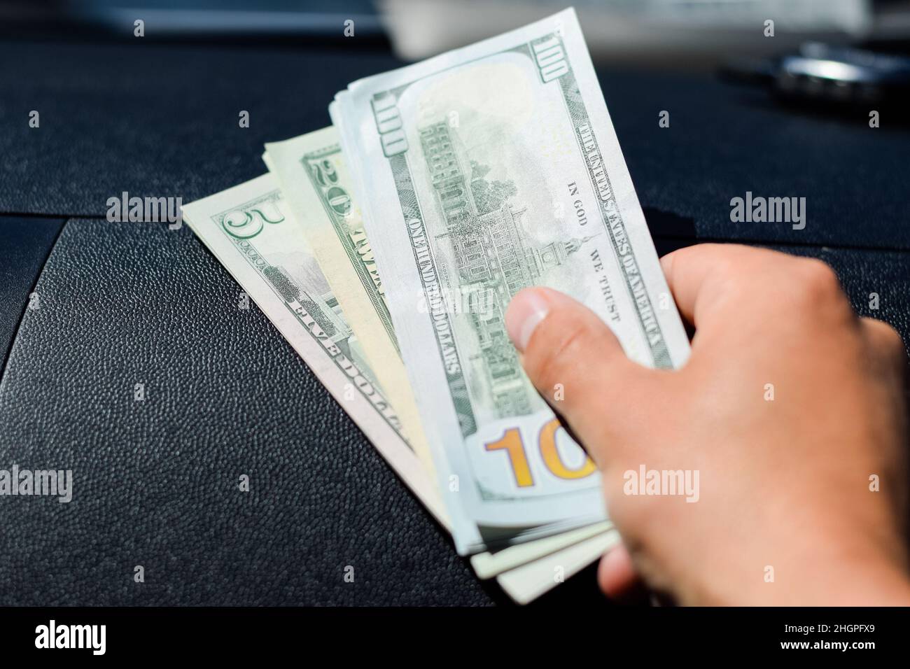 A man hands over money in a car. A wad of dollars in his hand Stock ...